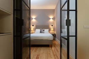 Quarto moderno com uma cama centralizada entre duas mesas de cabeceira, cada uma com uma luminária.