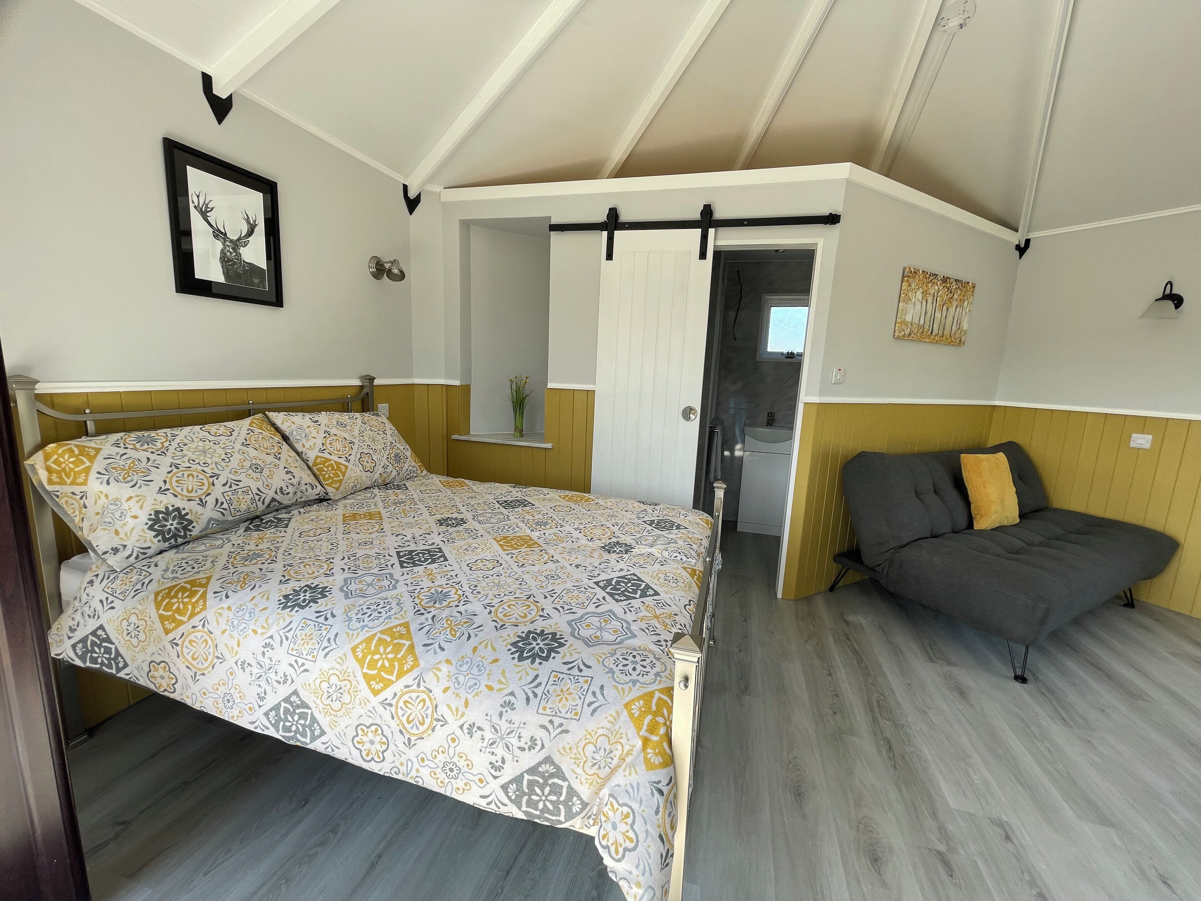 Quarto com cama, sofá, janela e porta que dá para um banheiro.