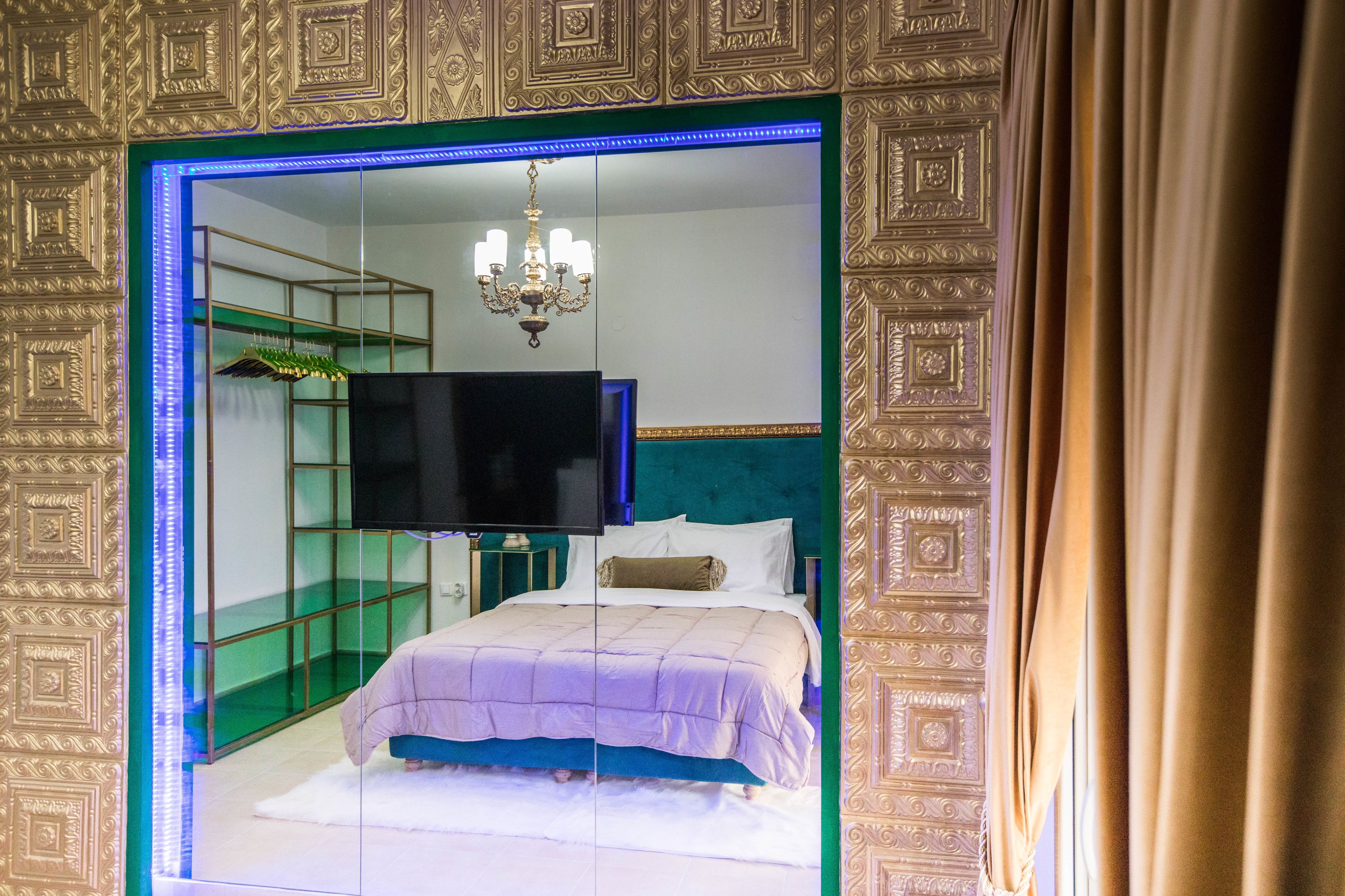 Quarto com cama, televisão e lustre.