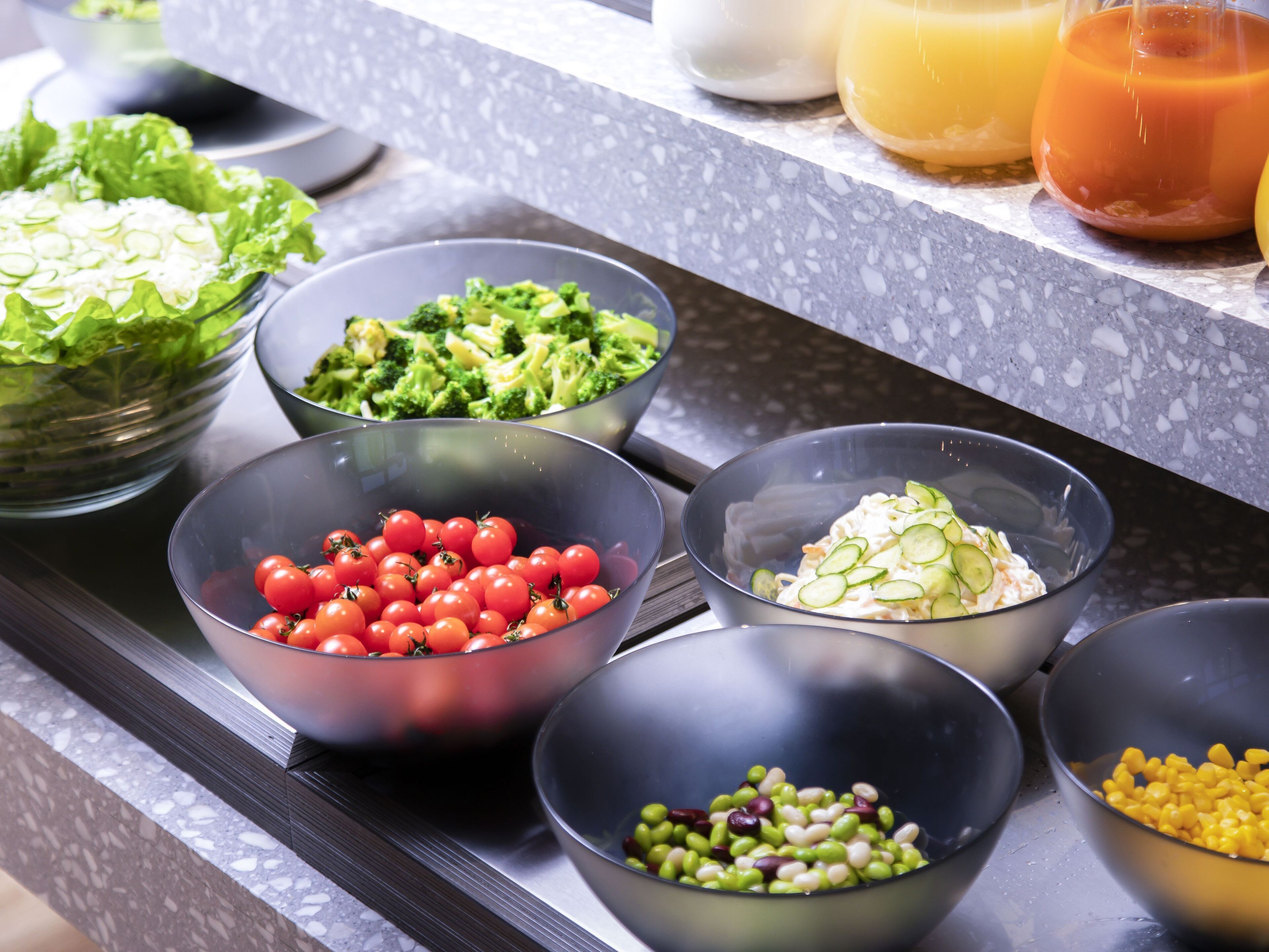Uma bancada de cozinha com várias tigelas contendo diferentes ingredientes como tomates, pepinos e feijão.