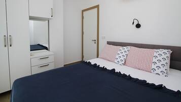 Quarto com cama, guarda-roupa, mesa de cabeceira e ar condicionado.
