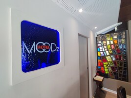 Placa de hotel com 'HOTEL DZ' e uma janela de vitrais colorida.