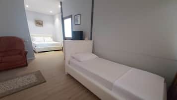 Quarto moderno e minimalista com uma cama de casal branca, uma poltrona vermelha e uma mesinha.