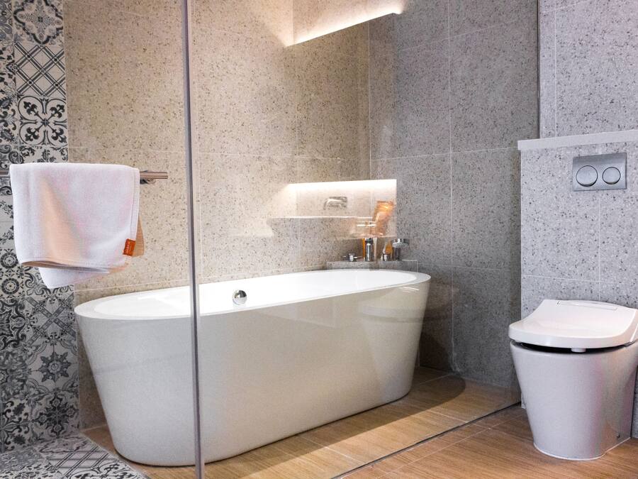 Um banheiro moderno com uma banheira independente, vaso sanitário e box de vidro.