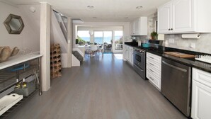 Cozinha moderna com armários brancos, eletrodomésticos de aço inoxidável e vista para o exterior.