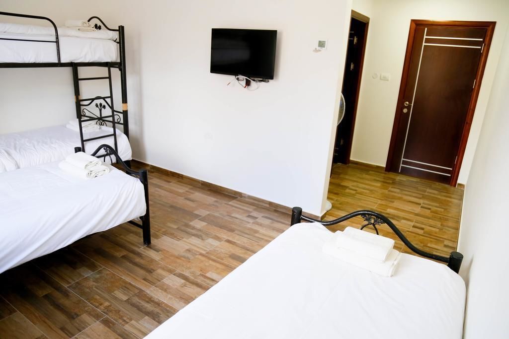 Quarto com beliches, televisão de tela plana e piso de madeira.