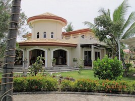 Uma casa de dois andares com uma seção central circular e telhado plano.
