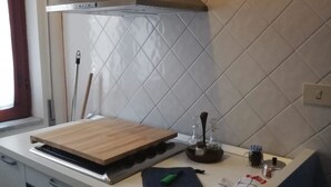 Uma cozinha com fogão, tábua de corte, faca, garrafa e caneca.