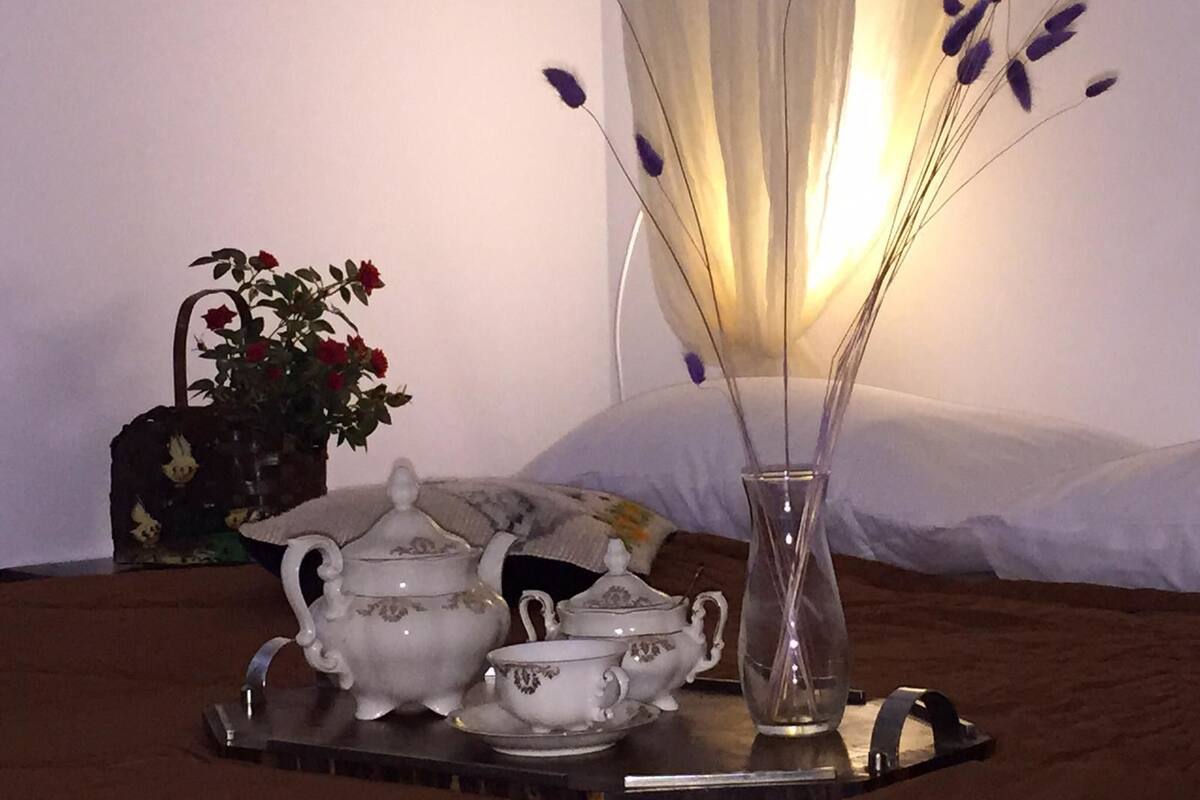 Uma mesa com um conjunto de chá, um vaso com flores e um objeto decorativo sobre uma bandeja.