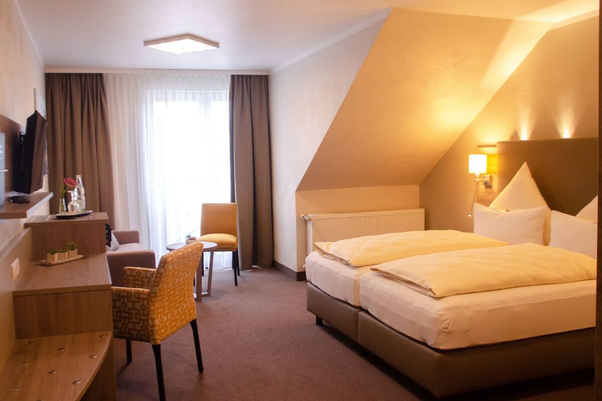 Quarto de hotel com uma cama, uma mesa, uma cadeira e uma televisão.