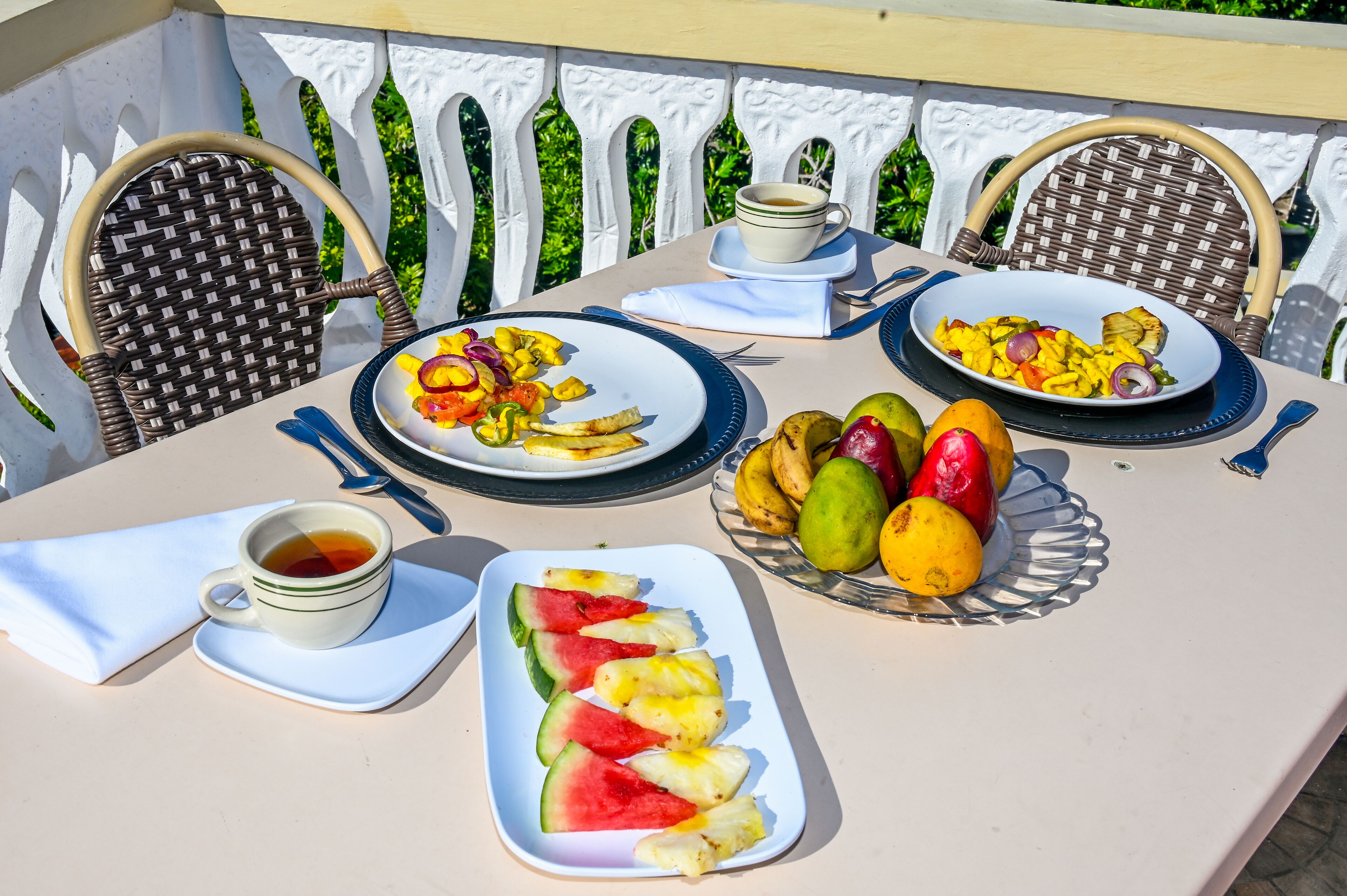 Uma mesa posta com pratos de fruta, uma chávena de chá e uma tigela de fruta.