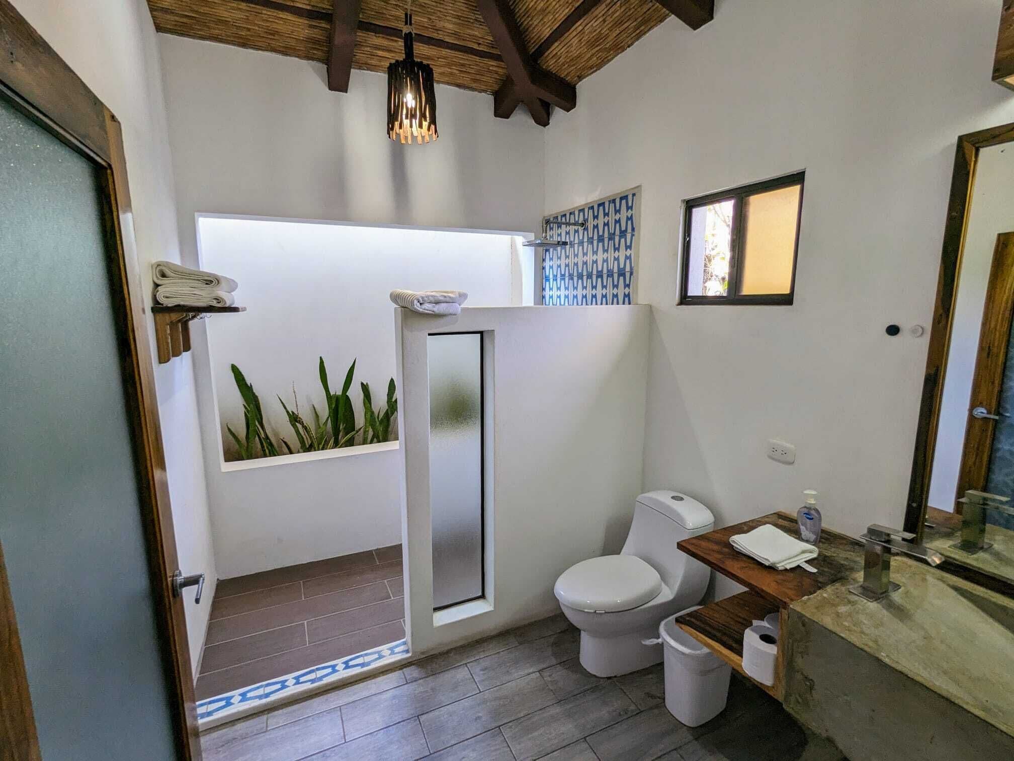 Casa de banho com chuveiro, sanita e lavatório.