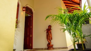 Interior de um edifício com teto de madeira, uma estátua e um vaso com planta.