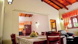 Uma sala de jantar com uma mesa posta para quatro pessoas, rodeada por cadeiras, e um ventilador de teto acima.