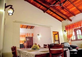 Uma sala de jantar com uma mesa posta para quatro pessoas, rodeada por cadeiras, e um ventilador de teto acima.