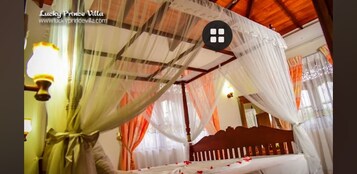 Quarto com cama de dossel, cabeceira de madeira e janela com cortinas.