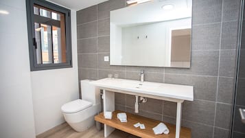Um banheiro moderno com pia branca, espelho e vaso sanitário.