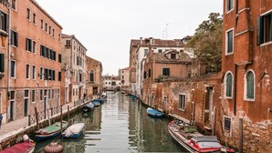 Um canal estreito ladeado por edifícios históricos, com barcos atracados nas margens.