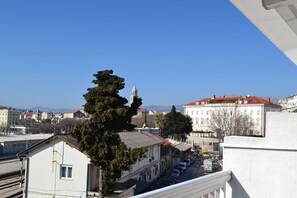 Paisagem urbana com edifícios, uma torre de igreja em destaque e céu azul límpido.