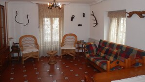 Uma sala de estar com móveis de vime, um sofá estampado e um lustre.
