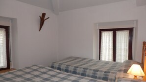 Quarto com duas camas, um adorno de parede de madeira e uma janela com cortinas.