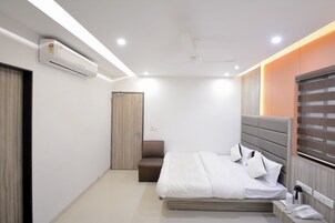 Quarto de hotel moderno com cama, mesa de cabeceira e aparelho de ar condicionado.