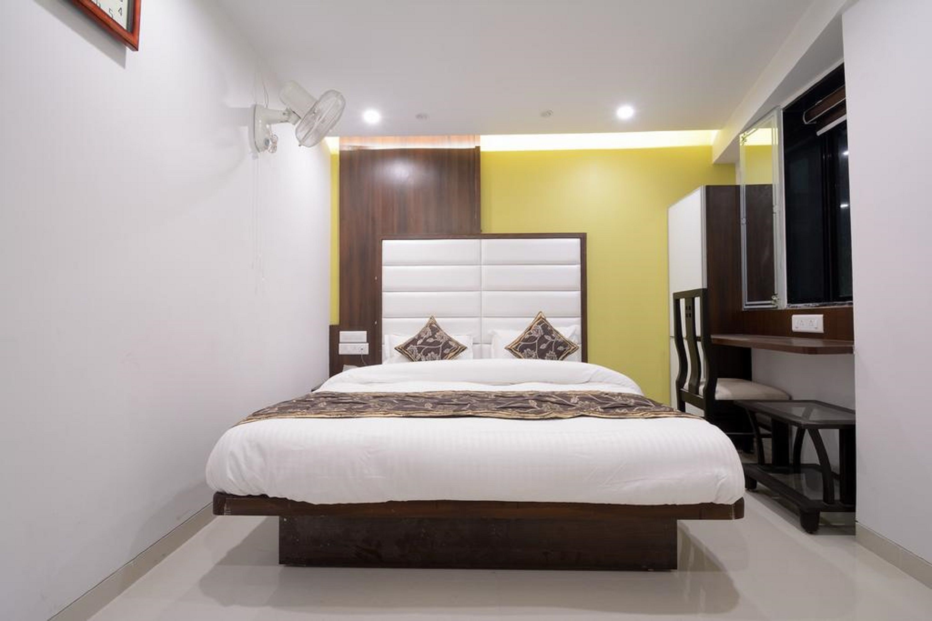 Quarto moderno com uma cama grande, uma mesa de cabeceira, uma cadeira e um espelho.