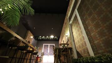 Uma área de bar interna com banquetas de madeira, parede de tijolos e porta com padrão.