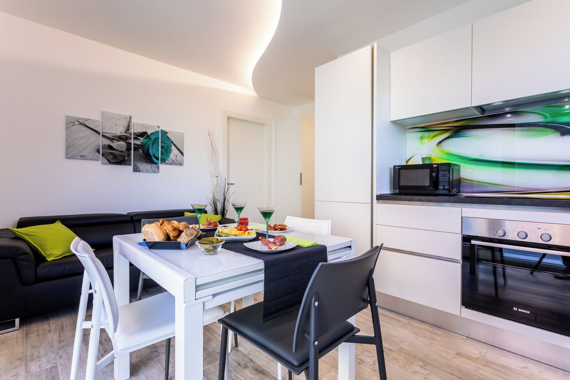 Uma cozinha moderna com forno Bosch, uma mesa de jantar com cadeiras e esquema de cores preto e branco.