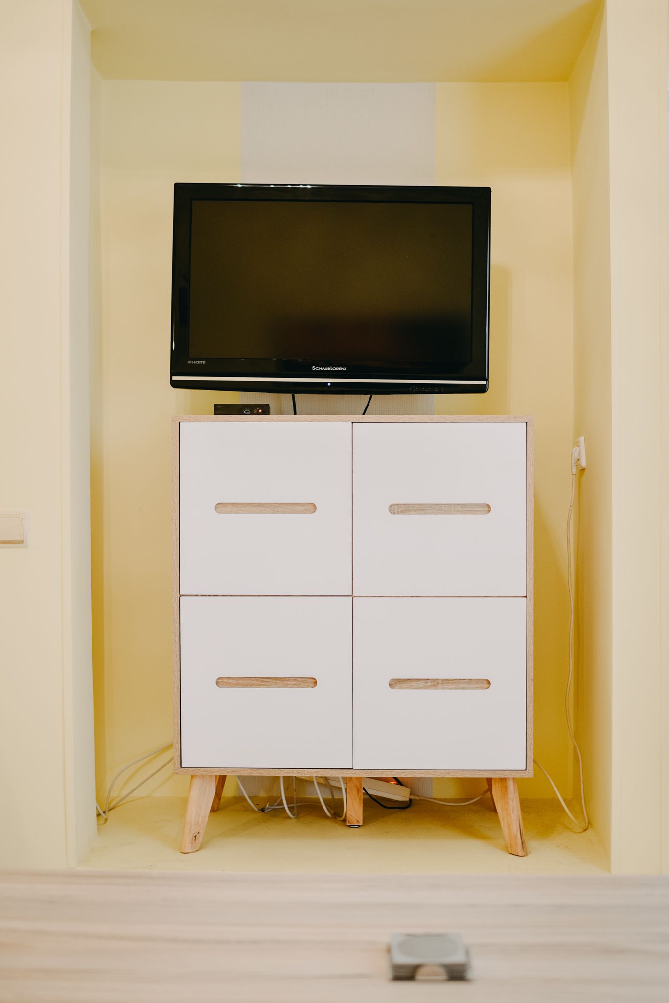 Um armário branco com gavetas e uma televisão de tela plana em cima.