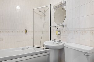 Uma casa de banho moderna com cabine de duche em vidro, uma sanita e lavatório branco.