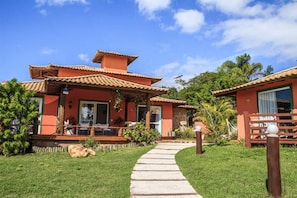 Um edifício em estilo tradicional com telhado de telhas, um caminho pavimentado que leva à entrada e um gramado bem cuidado.