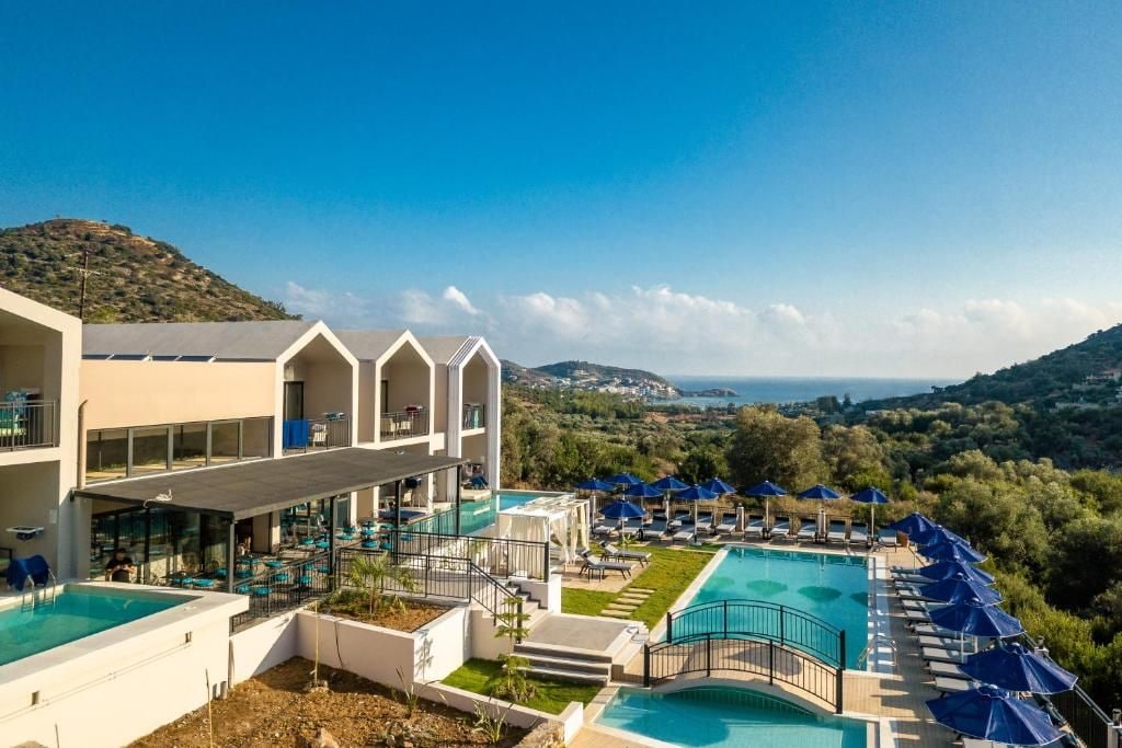 Um hotel com várias piscinas, áreas de estar ao ar livre e vista para a paisagem circundante.