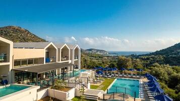 Um hotel com várias piscinas, áreas de estar ao ar livre e vista para a paisagem circundante.