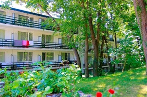 Um hotel de vários andares com varandas e um jardim.