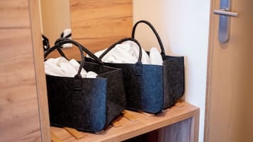 Duas bolsas pretas de feltro com alças sobre uma prateleira de madeira em um quarto.