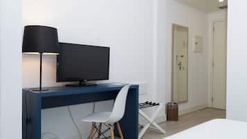 Quarto moderno com escrivaninha azul, cadeira branca, televisão de tela plana e luminária.