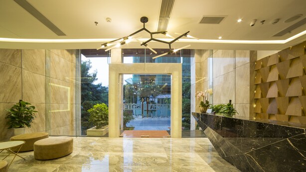 Um lobby moderno com piso de mármore, balcão de recepção e design geométrico na parede.