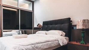Quarto moderno com uma cama grande, mesa de cabeceira, abajur e janela.