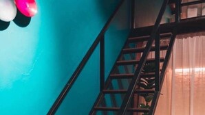 Uma escada com corrimão de metal preto, parede verde-água e piso de madeira.
