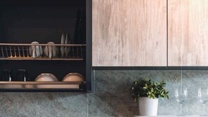 Uma cozinha moderna com painel de fundo de mármore, pia embutida e armários de madeira.