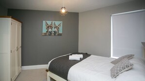 Quarto com cama, guarda-roupa, um quadro e um candeeiro suspenso.