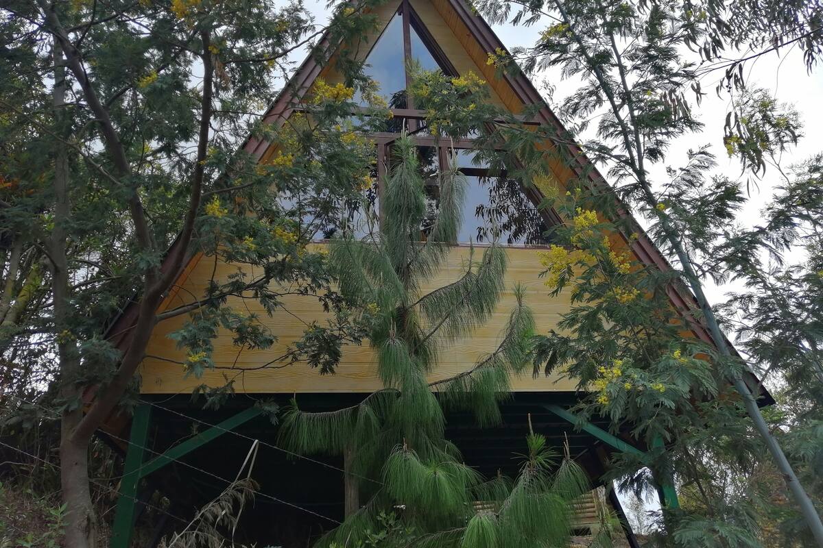 Uma estrutura de madeira triangular com uma grande janela e uma cruz no topo.