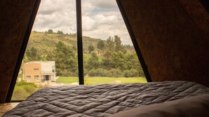 Uma cama com um edredom acolchoado em um quarto com vista para um edifício e uma colina.