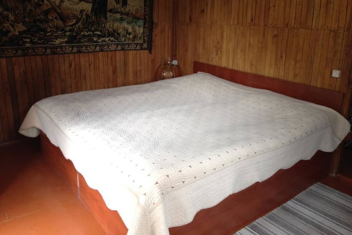 Um quarto com uma cama de madeira, um tapeçário estampado na parede e um tapete listrado.
