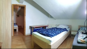 Um apartamento pequeno, com um quarto, uma cama, uma escrivaninha e uma cadeira.