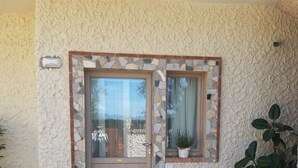Uma entrada de casa com fachada de pedra, porta de madeira e uma pequena janela.