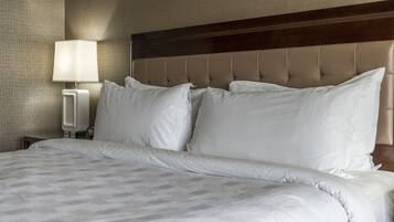Uma cama bem arrumada com cabeceira, abajur e relógio de parede.