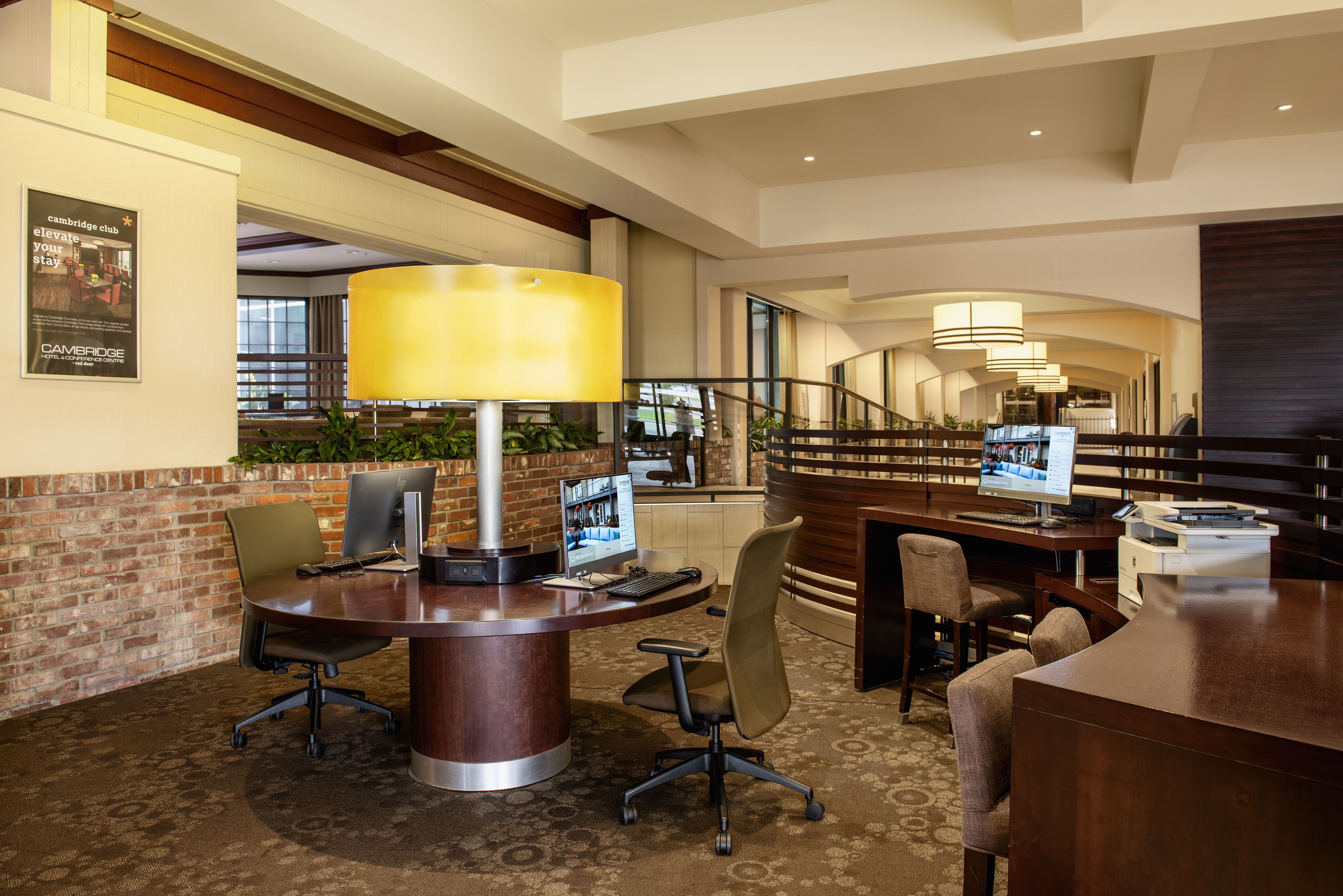 Um hall de hotel moderno com balcão de recepção, computadores e áreas de estar.