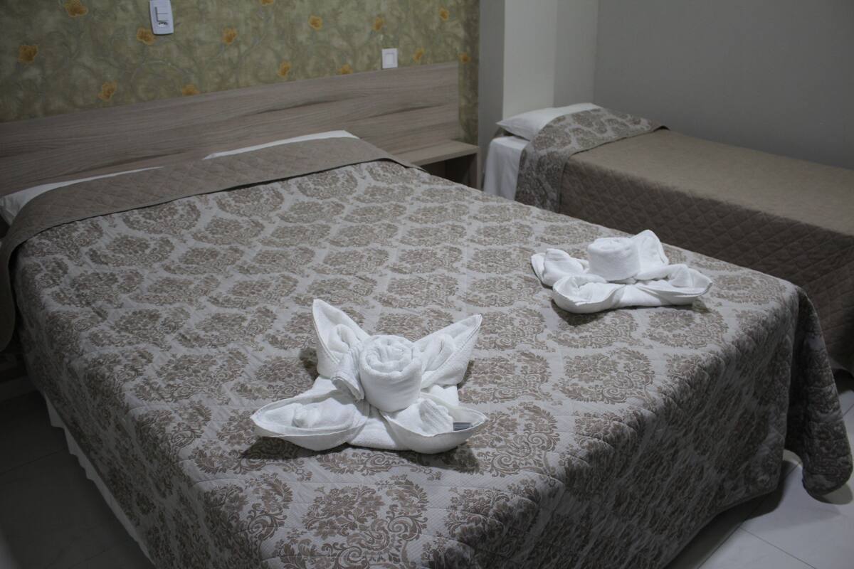 Quarto de hotel com duas camas, cada uma com roupa de cama estampada.